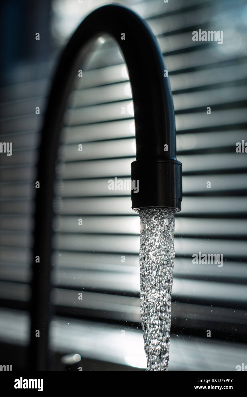 Water pouring from a modern kitchen tap Stock Photo - Alamy
