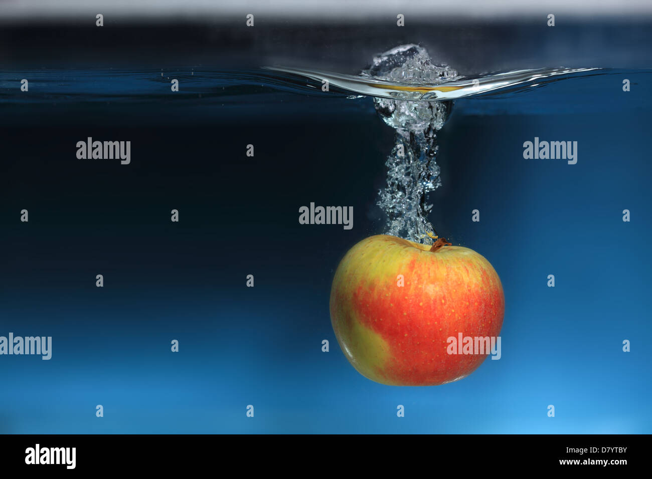 Yellow red apple in the water splash over blue background. Healthy food ...