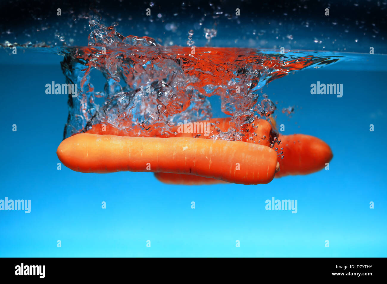 Carrot in the water splash over blue background. Healthy food and ...