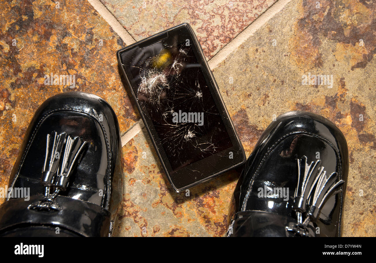 A smartphone lies broken between the shoes of its businesswoman owner ...