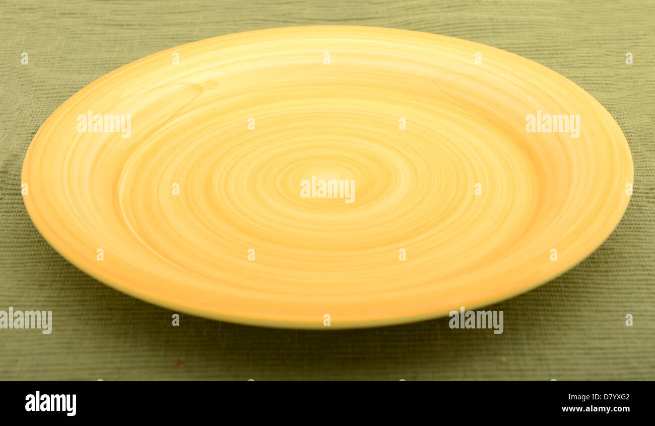 empty yellow plate on a green textured background Stock Photo - Alamy
