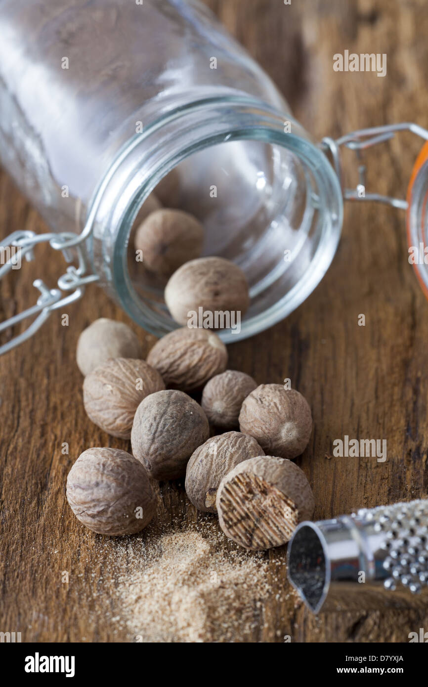 Many nutmegs are an empty spice jar on a rustic wooden background Stock ...
