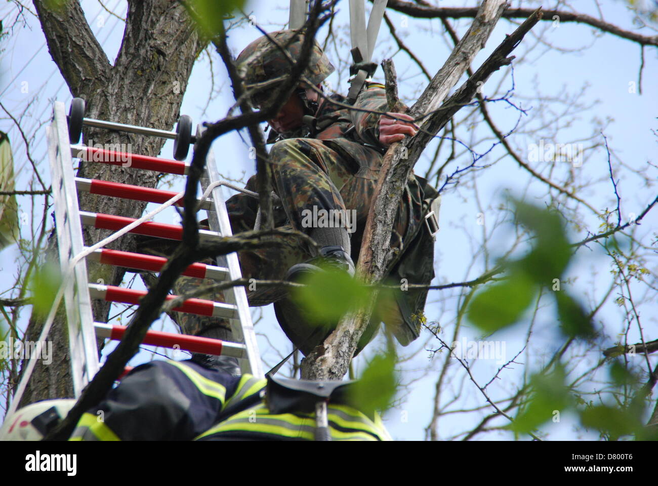 A firefighter climps up a tree to save a soldier of the German Armed ...