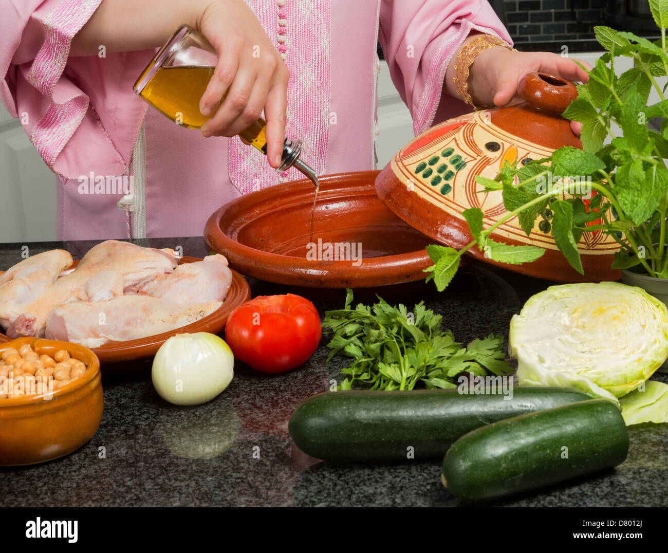 Traditional Moroccan immigrant woman in Europe adding olive oil to her ...