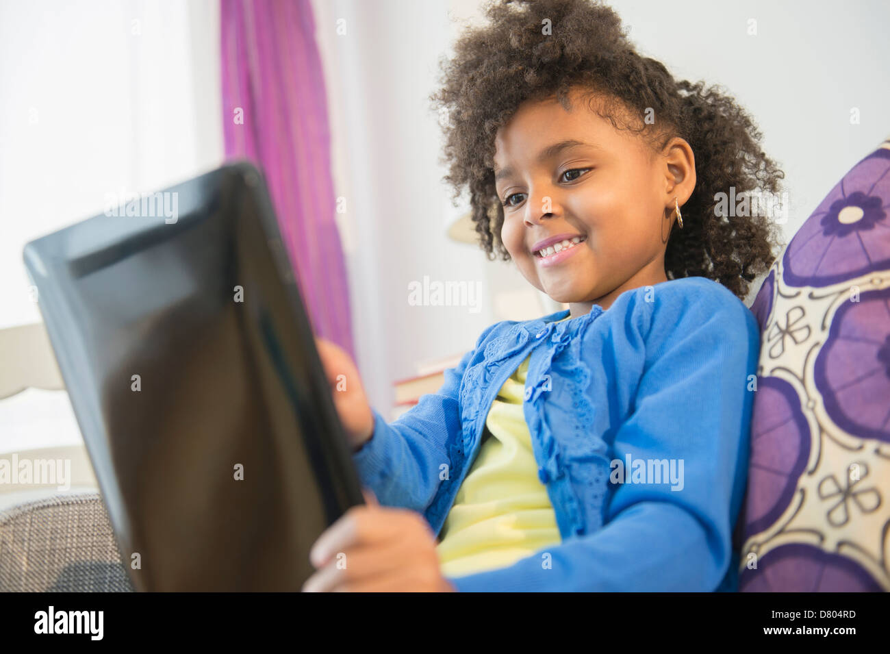 African American girl using tablet computer on sofa Stock Photo - Alamy