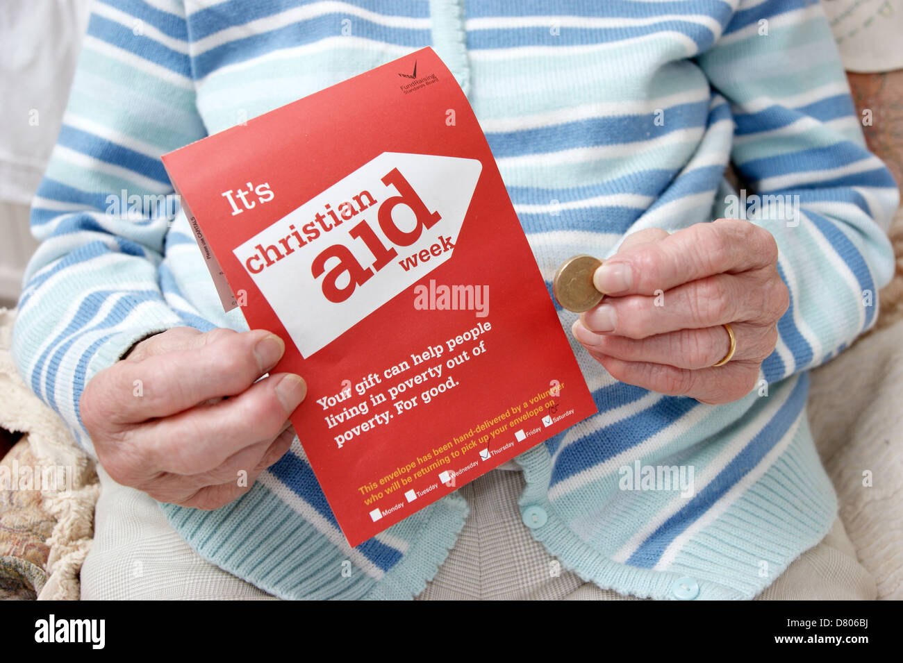 Woman holding donation of a £1 coin for a charity collecting envelope ...