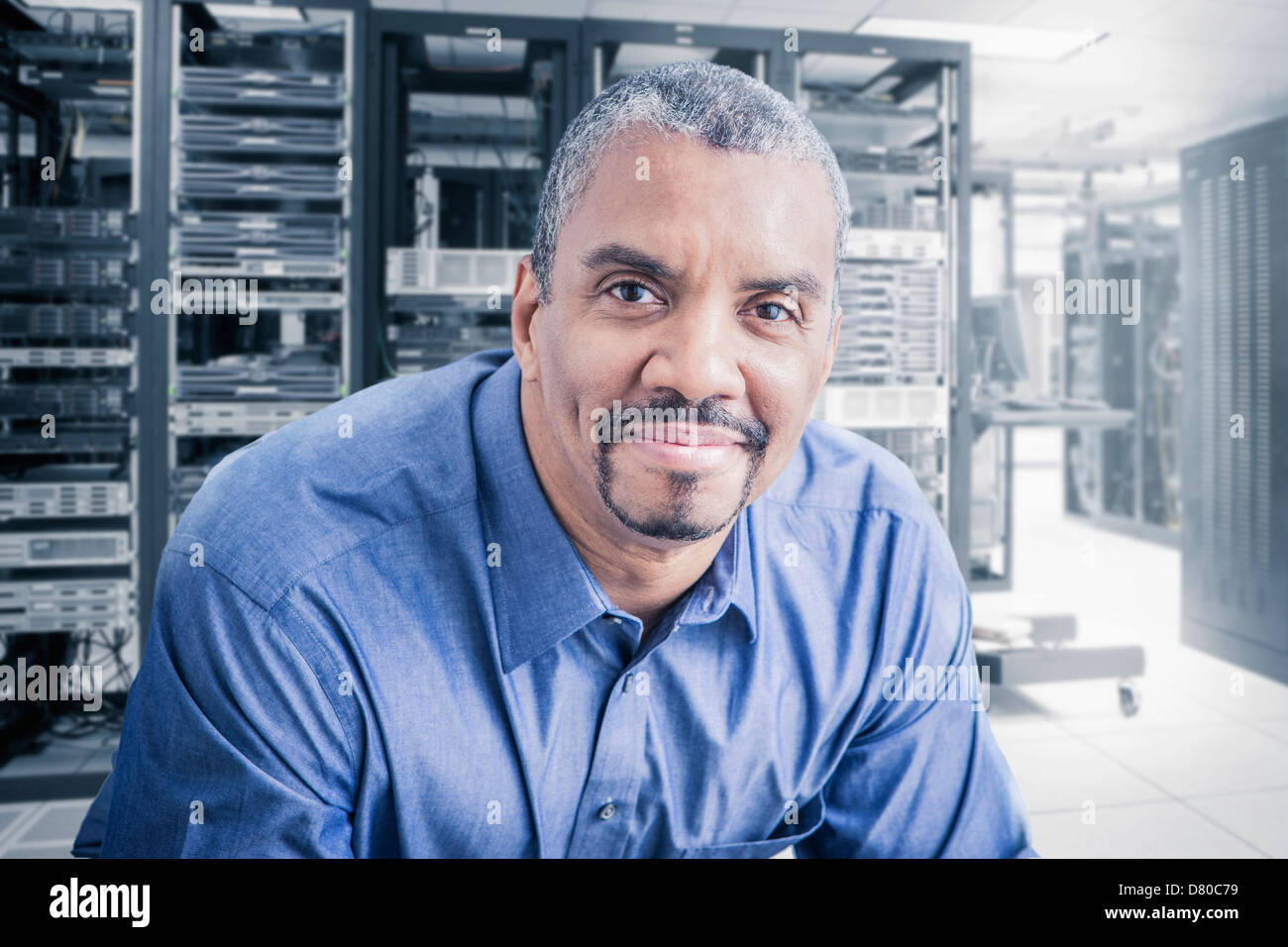 Mixed race businessman sitting in server room Stock Photo - Alamy