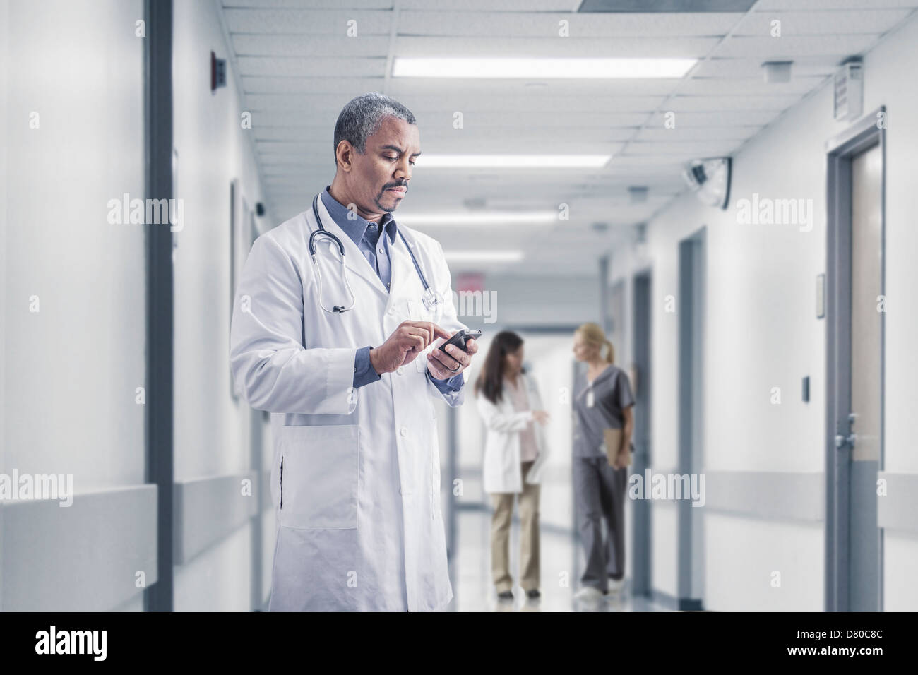Mixed race doctor using cell phone in hospital Stock Photo - Alamy