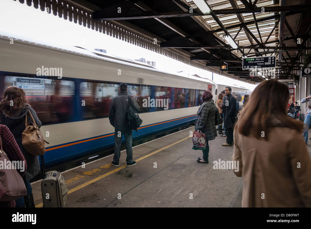 Passengers waiting for still moving train at station Stock Photo - Alamy