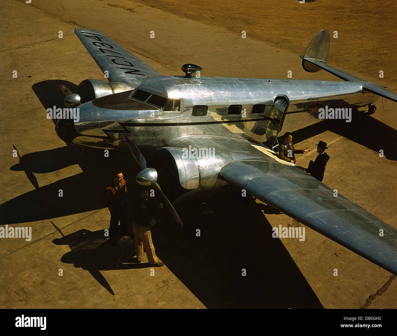 A photograph showing two men at the propeller of a Lockheed 12 Electra ...