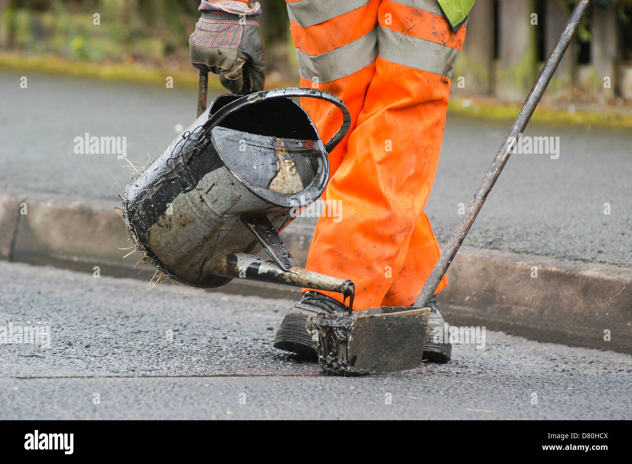 Tar being tipped on a road from a watering can, Walsall, West Midlands ...