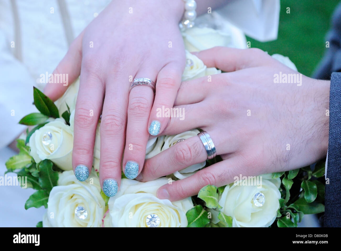 Close-up of bride and grooms hands on wedding day showing ring detail ...