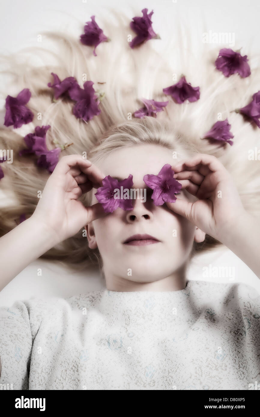 beautiful blond girl with flowers in her hair and in front of her eyes ...
