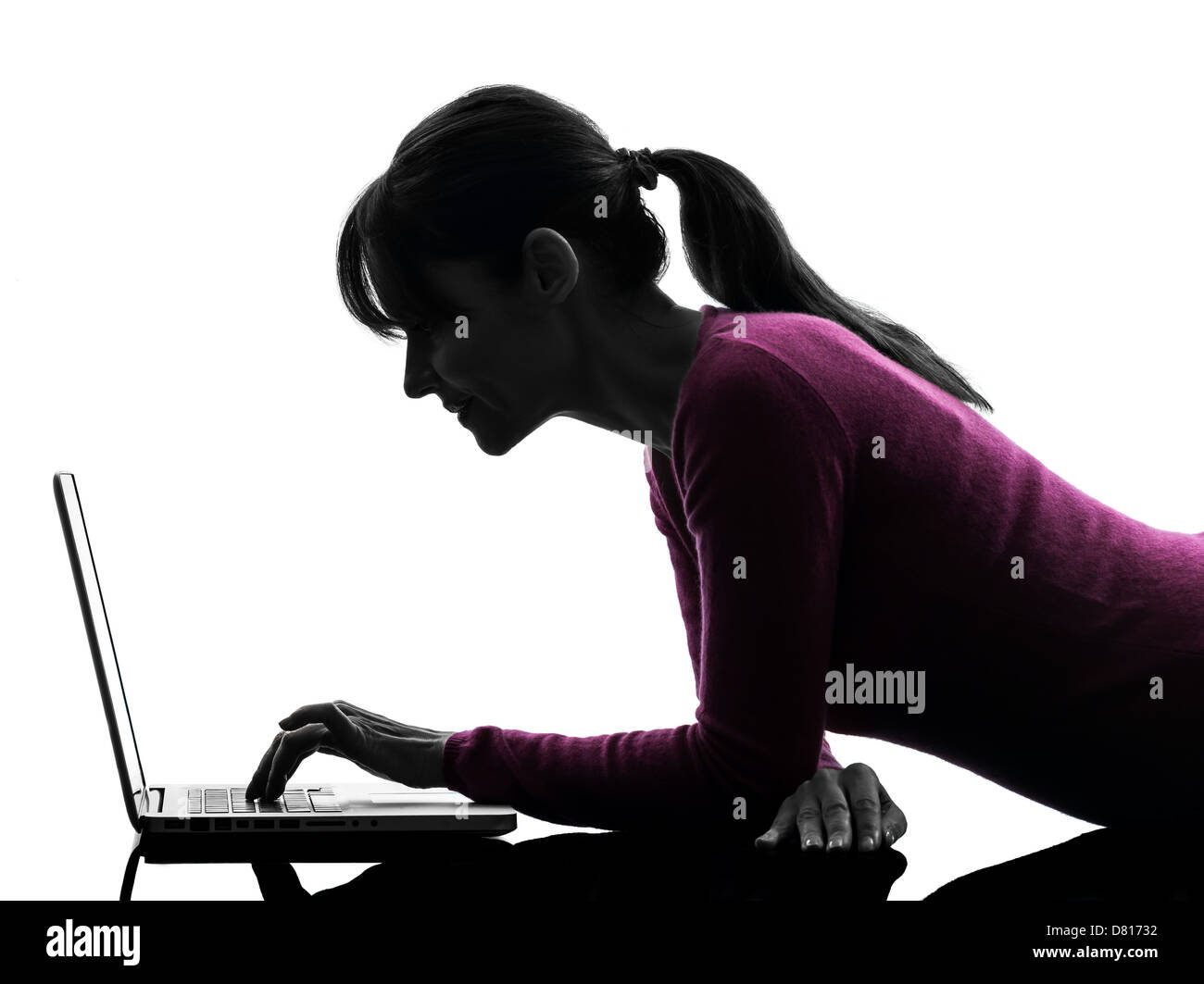 one woman serious computing laptop computer in silhouette studio ...