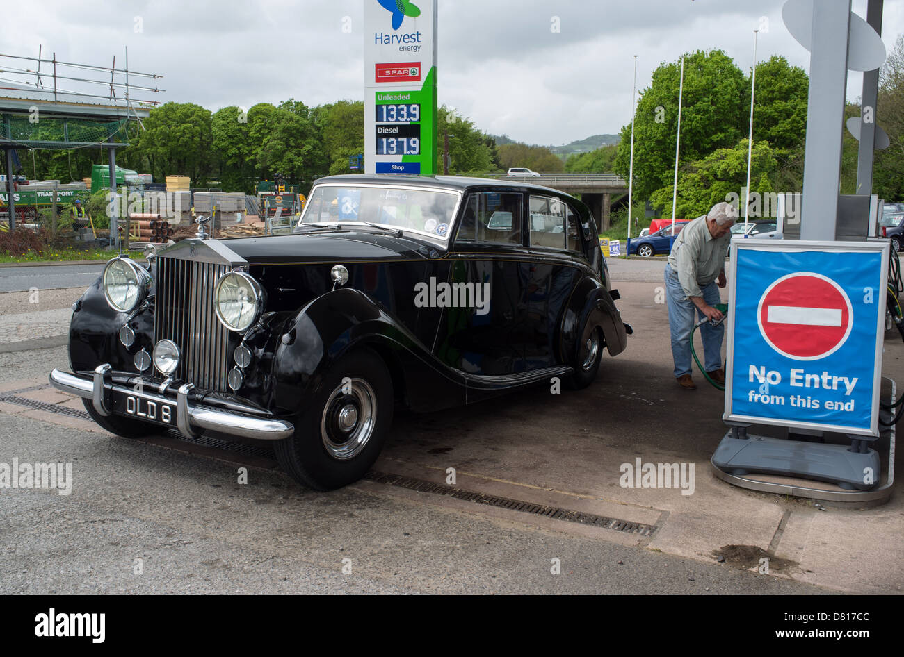 Honiton, Devon, England. A man fills his Rolls Royce up with petrol ...