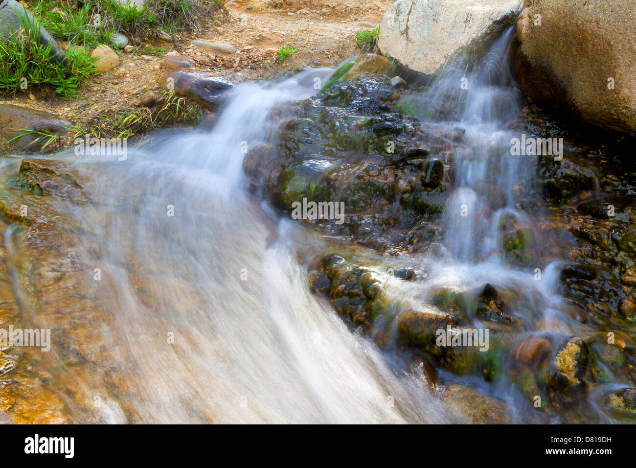 Warm water flows in a curve over yellow rocks in a waterfall at Kirkham ...