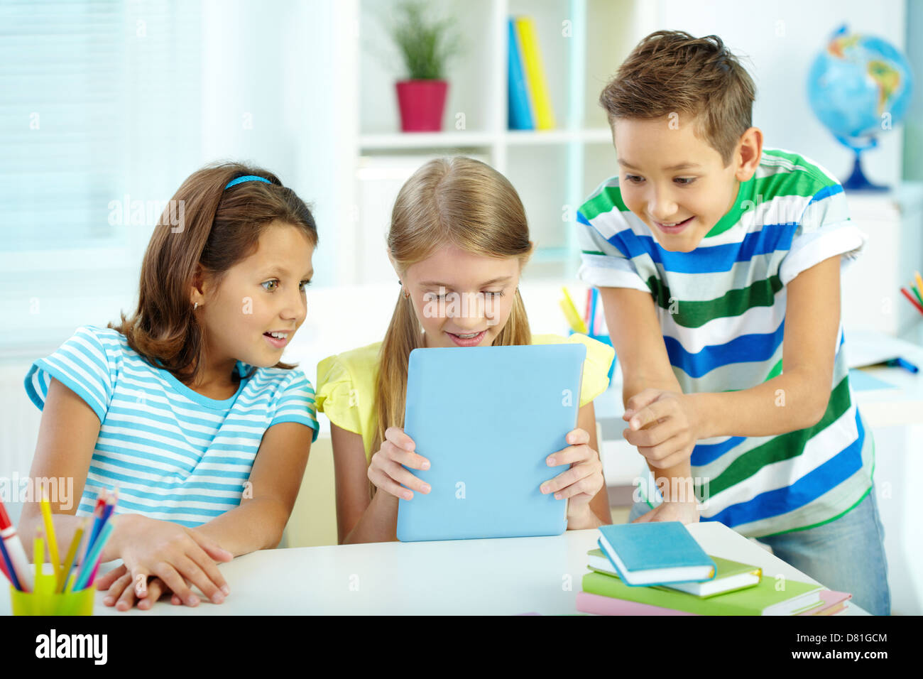 Portrait of happy classmates at workplace using digital tablet Stock ...