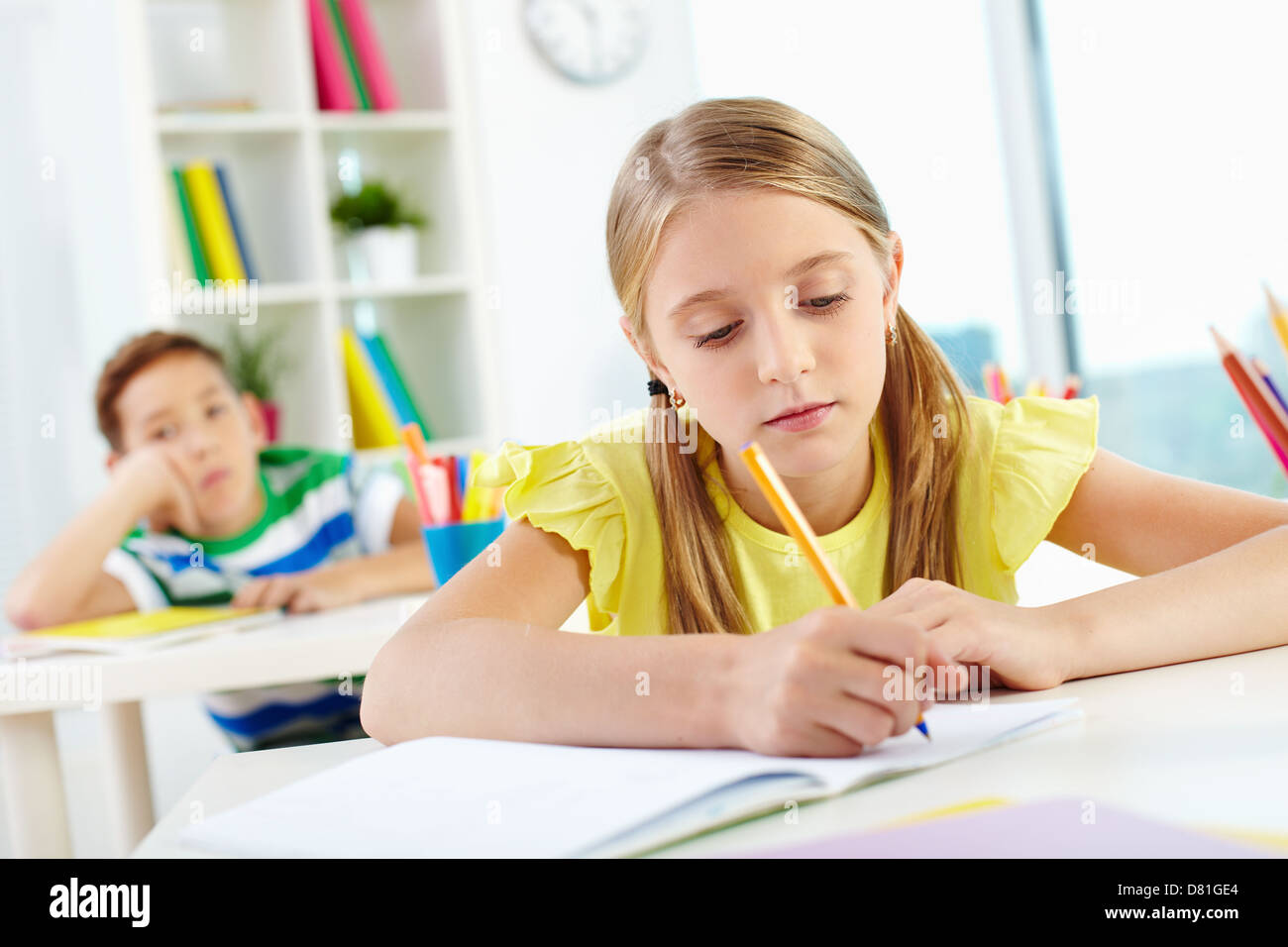 Portrait of lovely girl drawing at workplace with schoolmate on ...