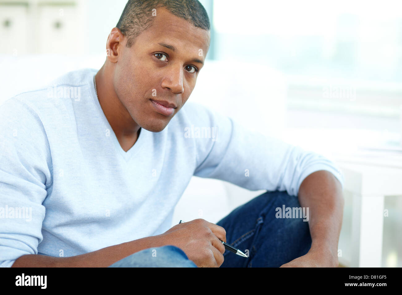 Image of pensive African man with pen looking at camera Stock Photo - Alamy