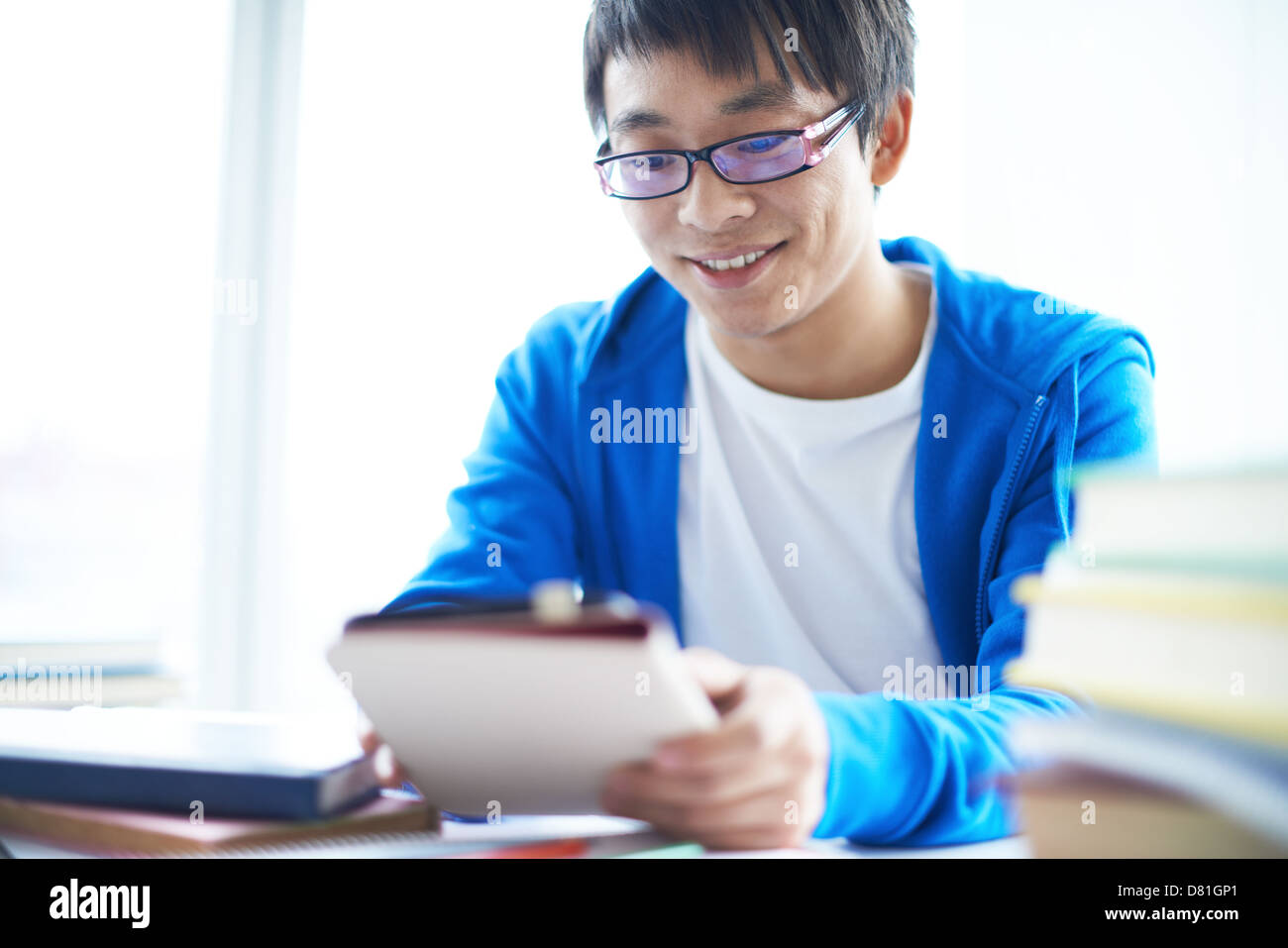 Portrait of successful Asian student in eyeglasses working at lesson ...