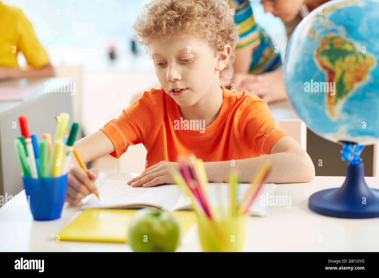 Portrait of cute schoolboy drawing at workplace during lesson Stock ...