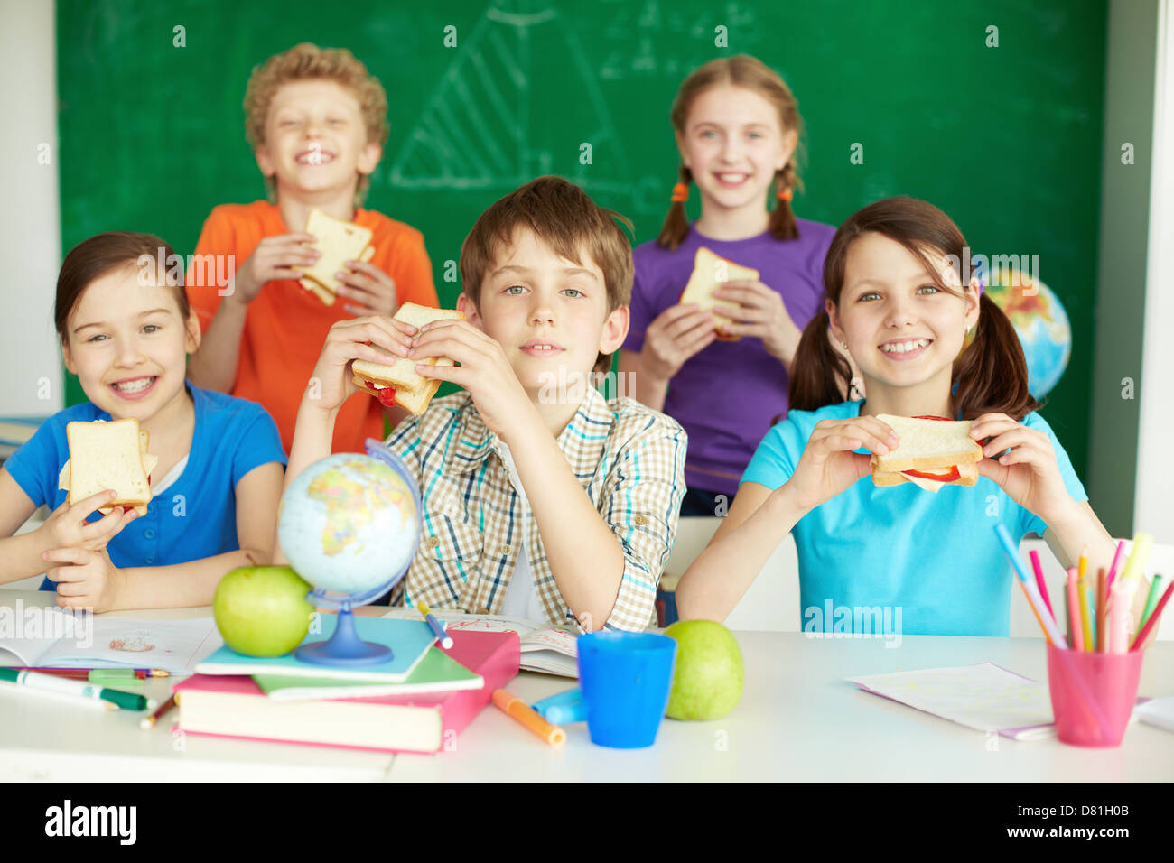Portrait of cute schoolchildren with sandwiches looking at camera in ... Portrait of cute schoolchildren with sandwiches looking at camera in ...