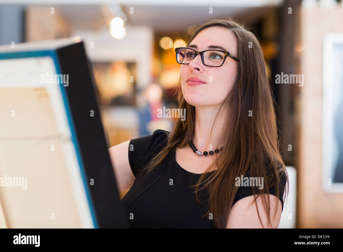 Caucasian woman examining painting in art gallery Stock Photo - Alamy