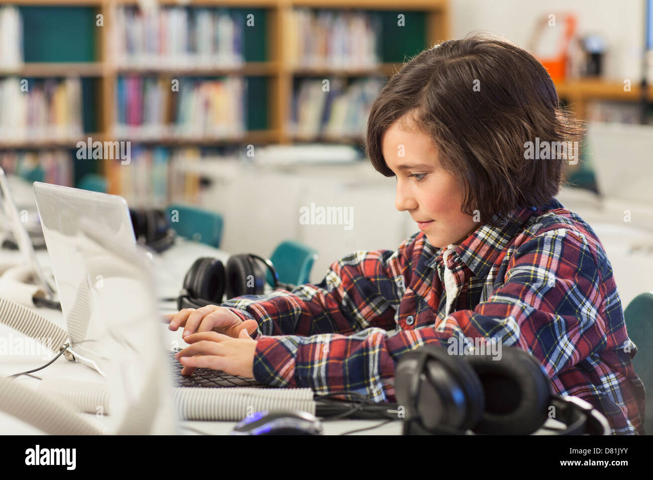 Caucasian boy using laptop in library Stock Photo - Alamy