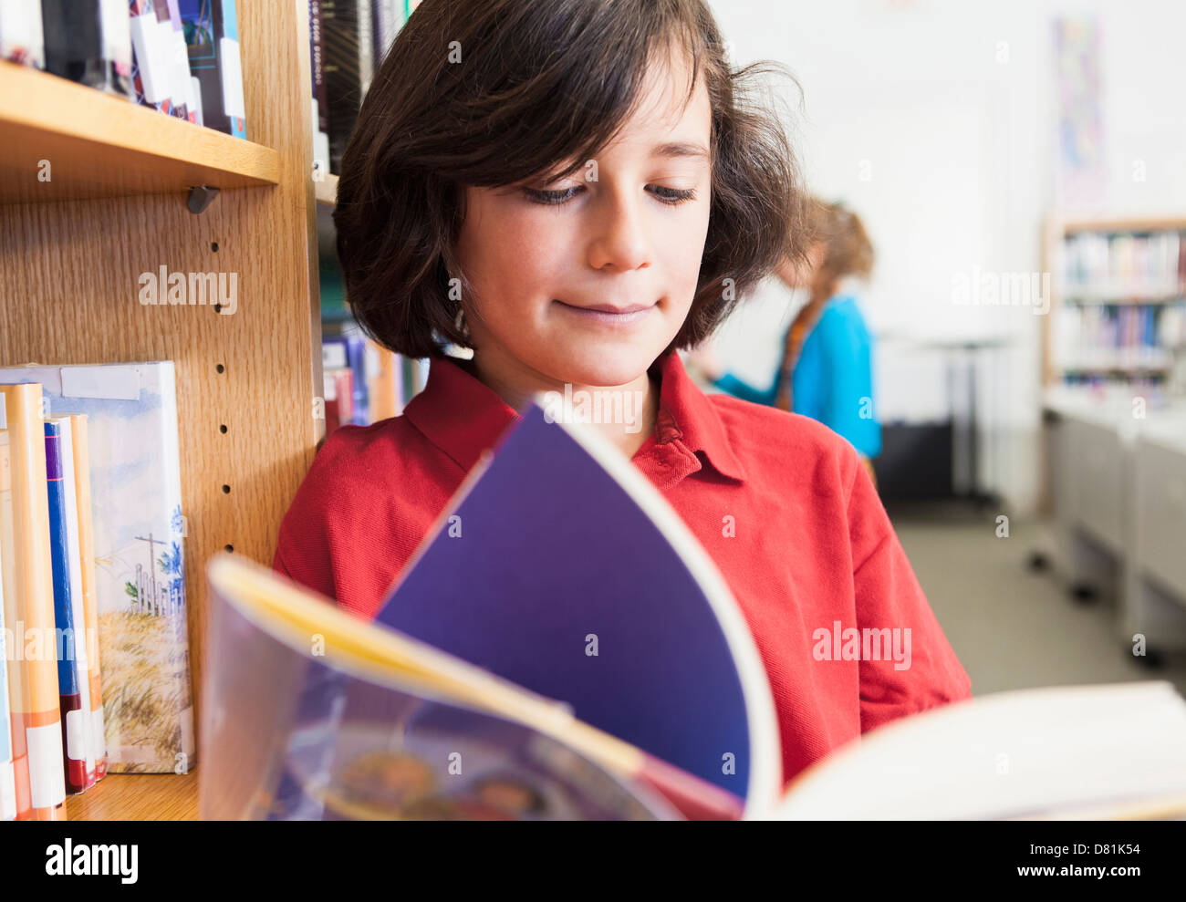 Caucasian boy reading book in library Stock Photo - Alamy