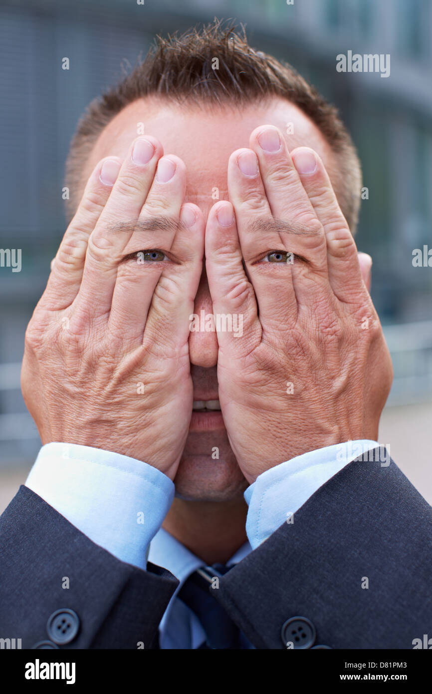 Business man with eyes on his hands over his face Stock Photo - Alamy