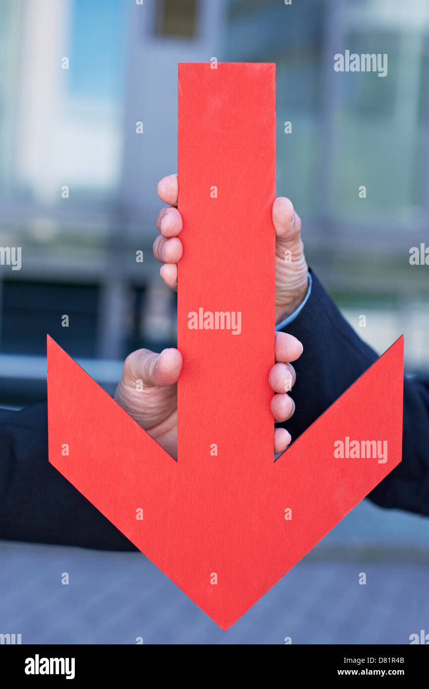 Two business hands holding a red arrow pointing down Stock Photo - Alamy