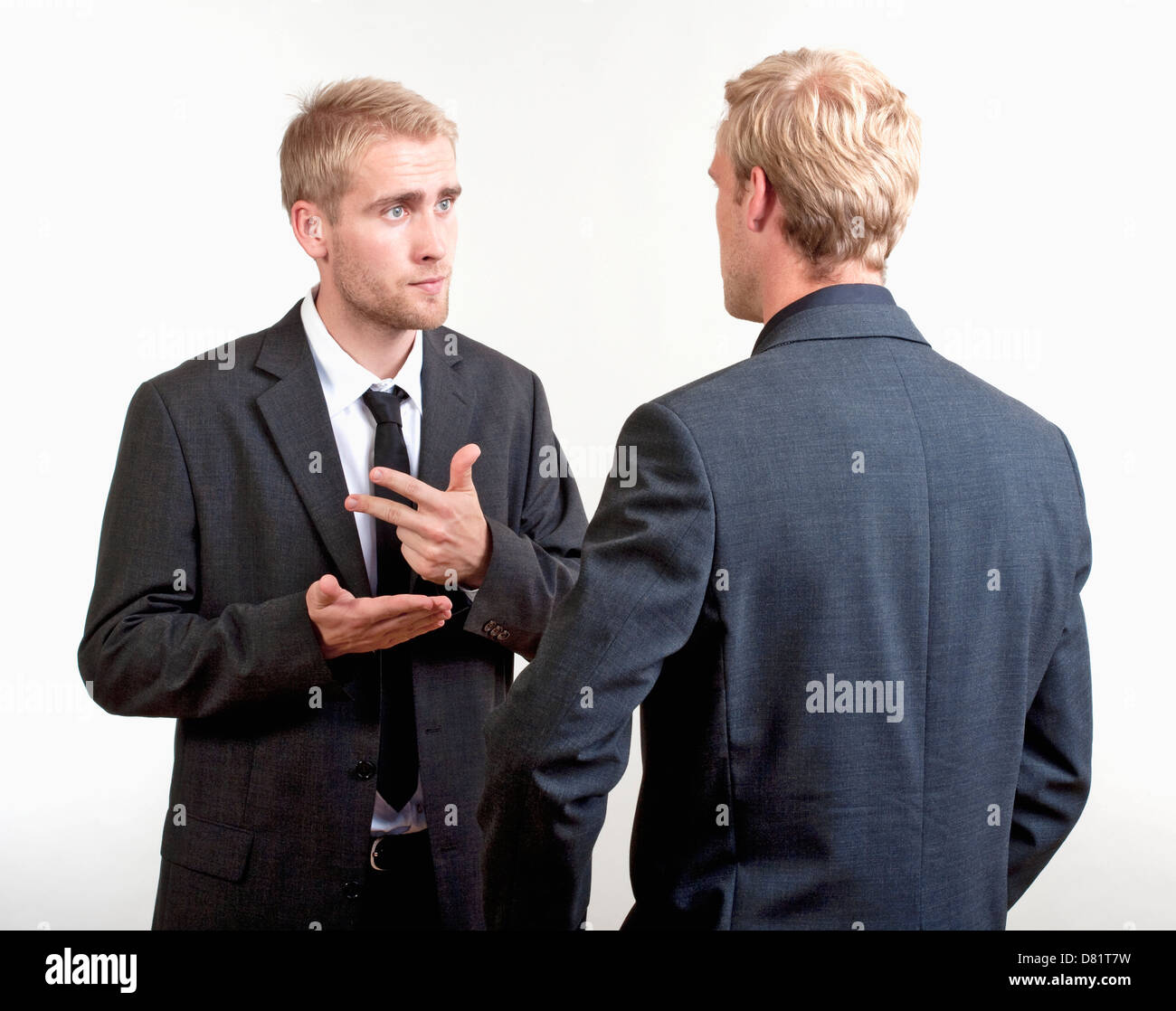 two young businessmen standing, discussing, arguing - isolated on light ...