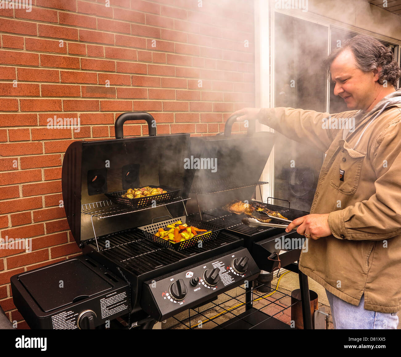 Male is repairing dinner on his smoking Barbecue loaded with chicken ...