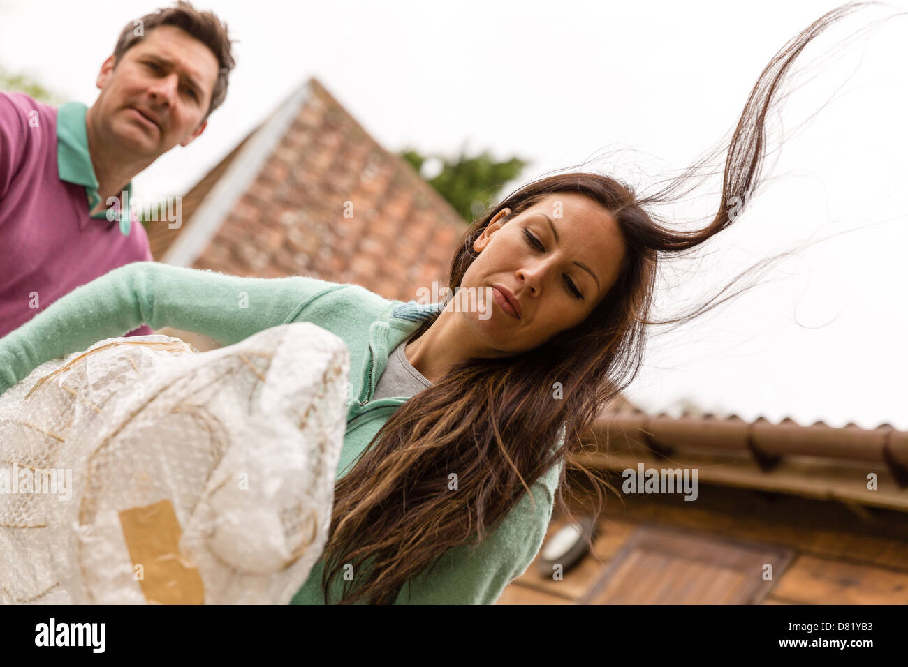 Man and woman carrying wrapped item Stock Photo - Alamy