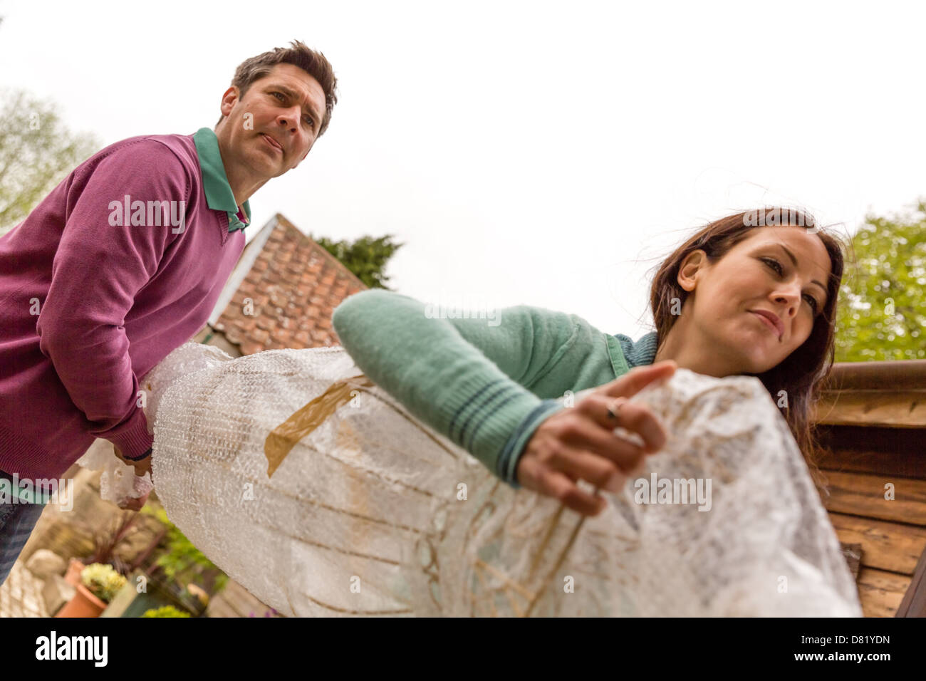 Man and woman carrying wrapped item Stock Photo - Alamy