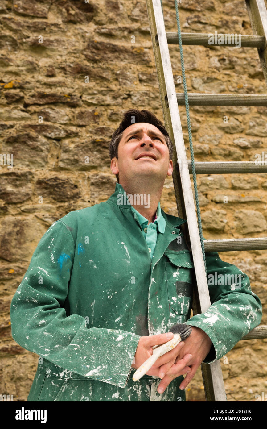 Man leaning on ladder holding paintbrush and looking up Stock Photo - Alamy