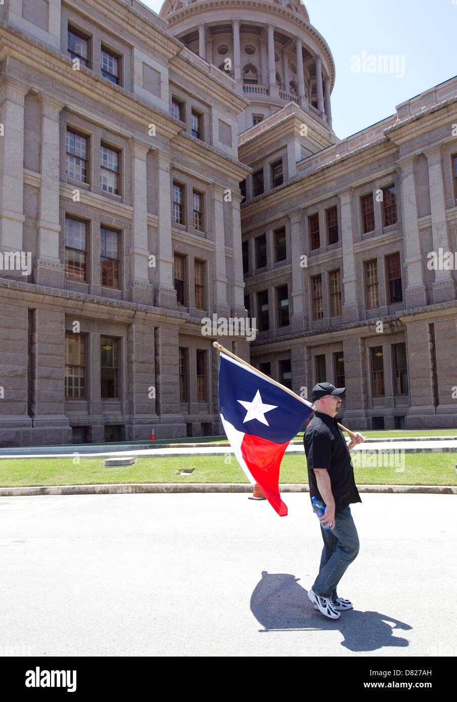 White male carries a Texas flag outside the Texas Capitol building in ...