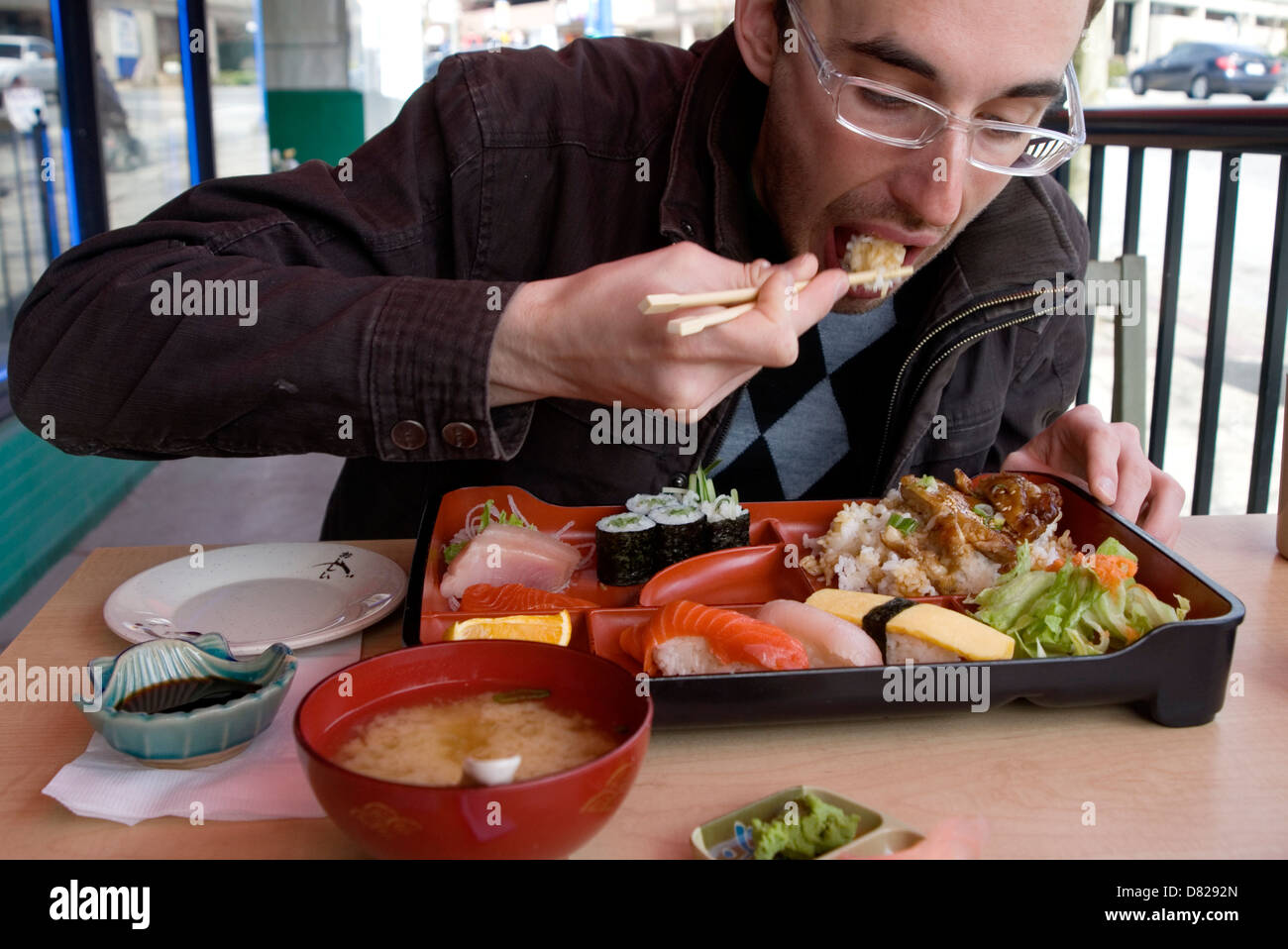 Caucasian man eating traditional bento box sushi at outdoor cafe with ...