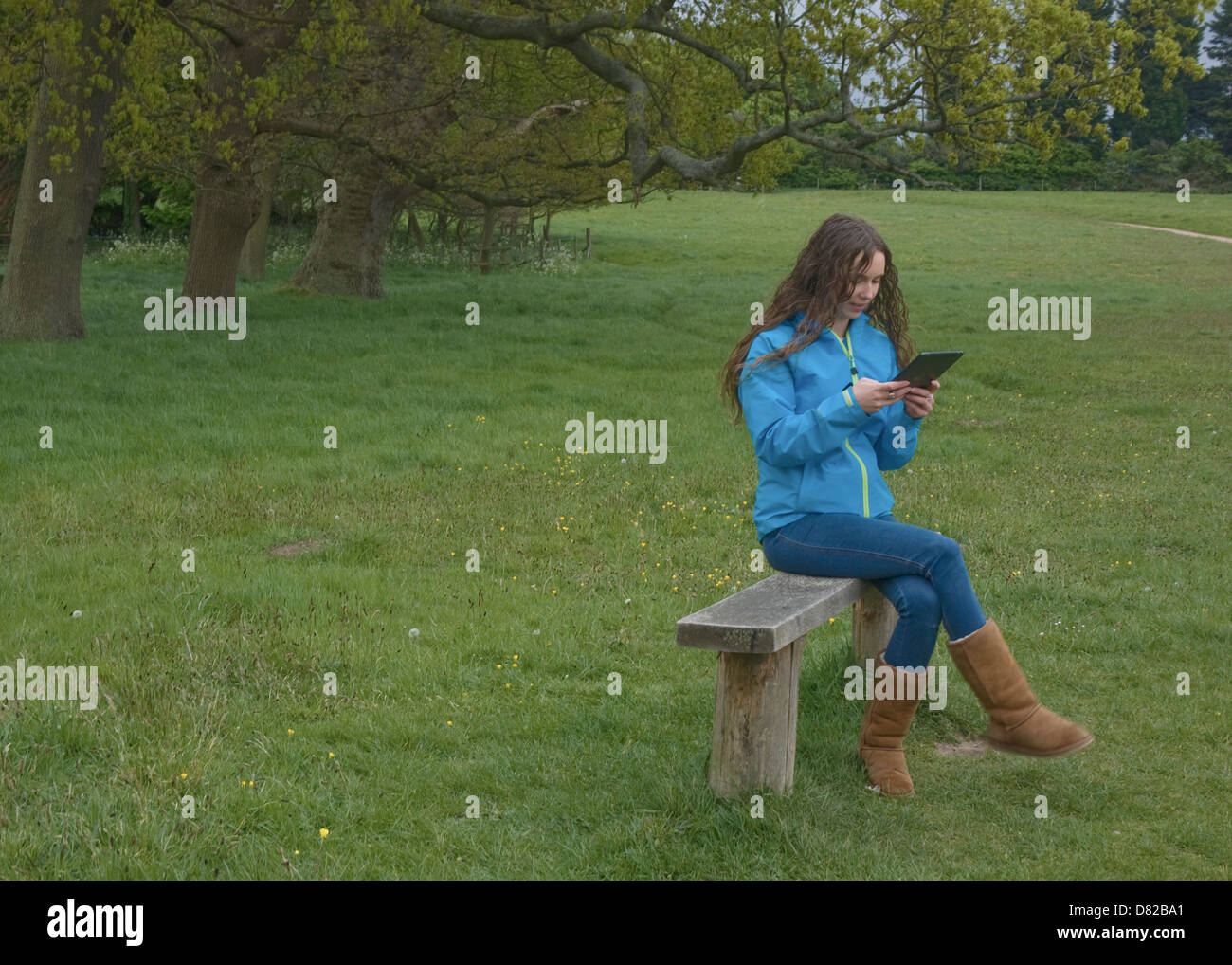 Young woman using iPad on bench in park Stock Photo - Alamy