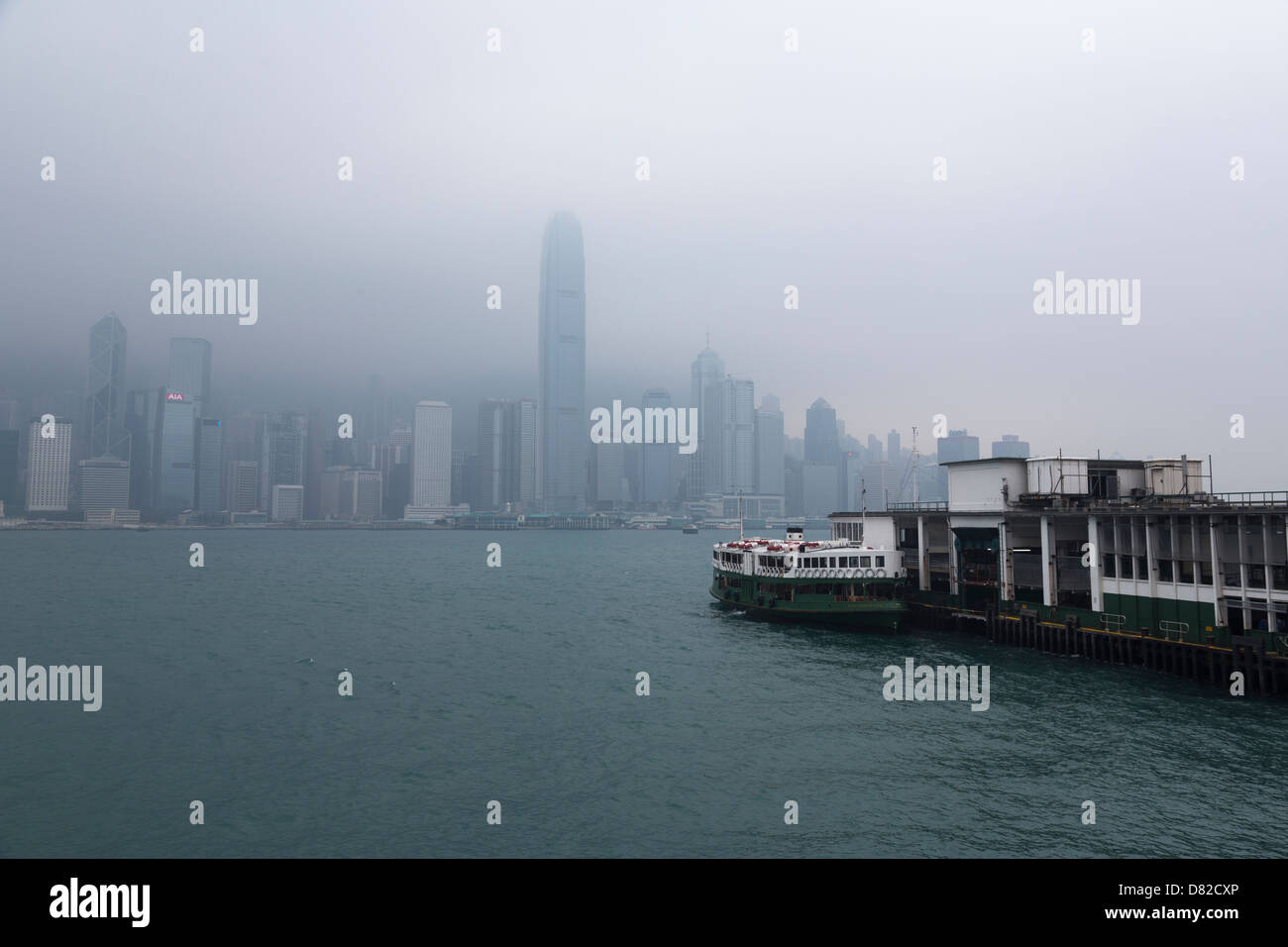 Star ferry at the Kowloon jetty with Hong Kong island skyline on a hazy ...