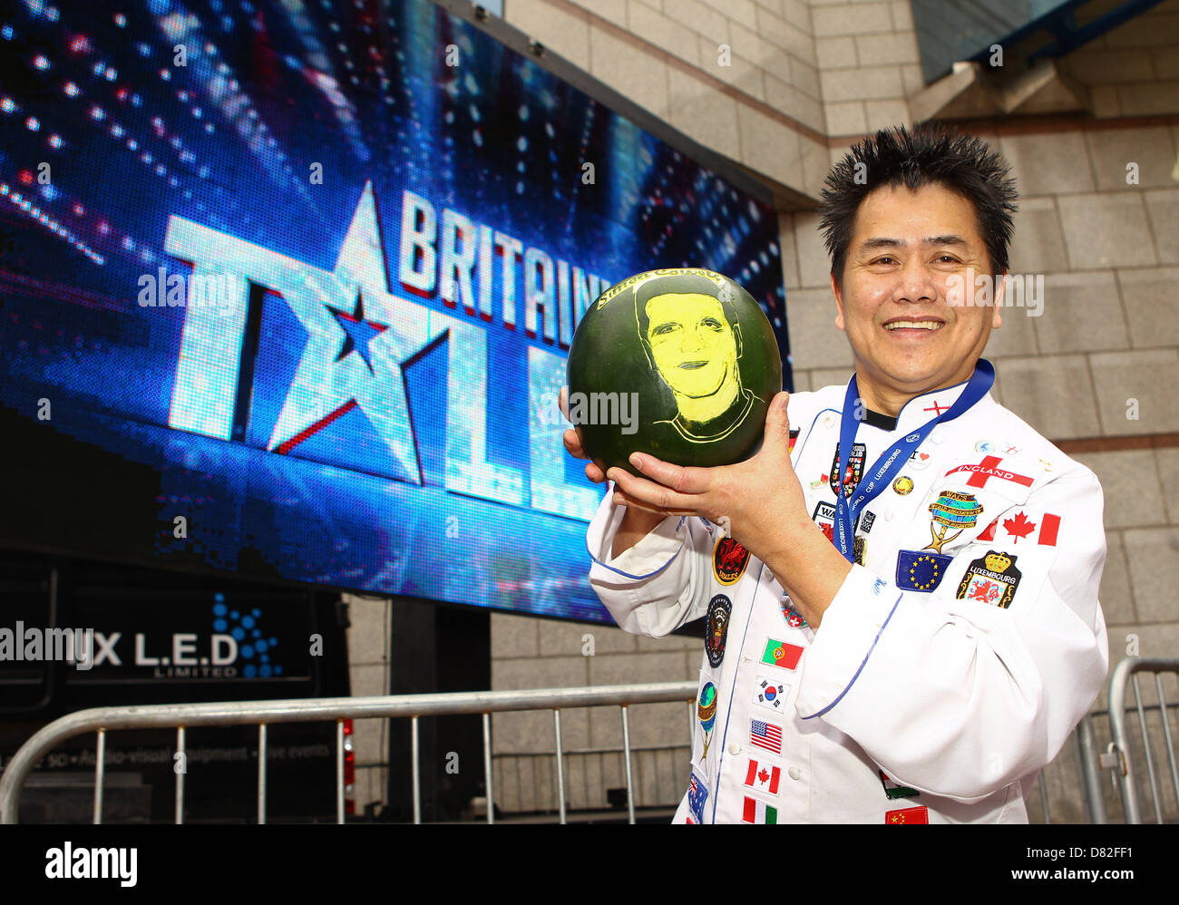 A man shows off a melon featuring the face of Simon Cowell at the ...