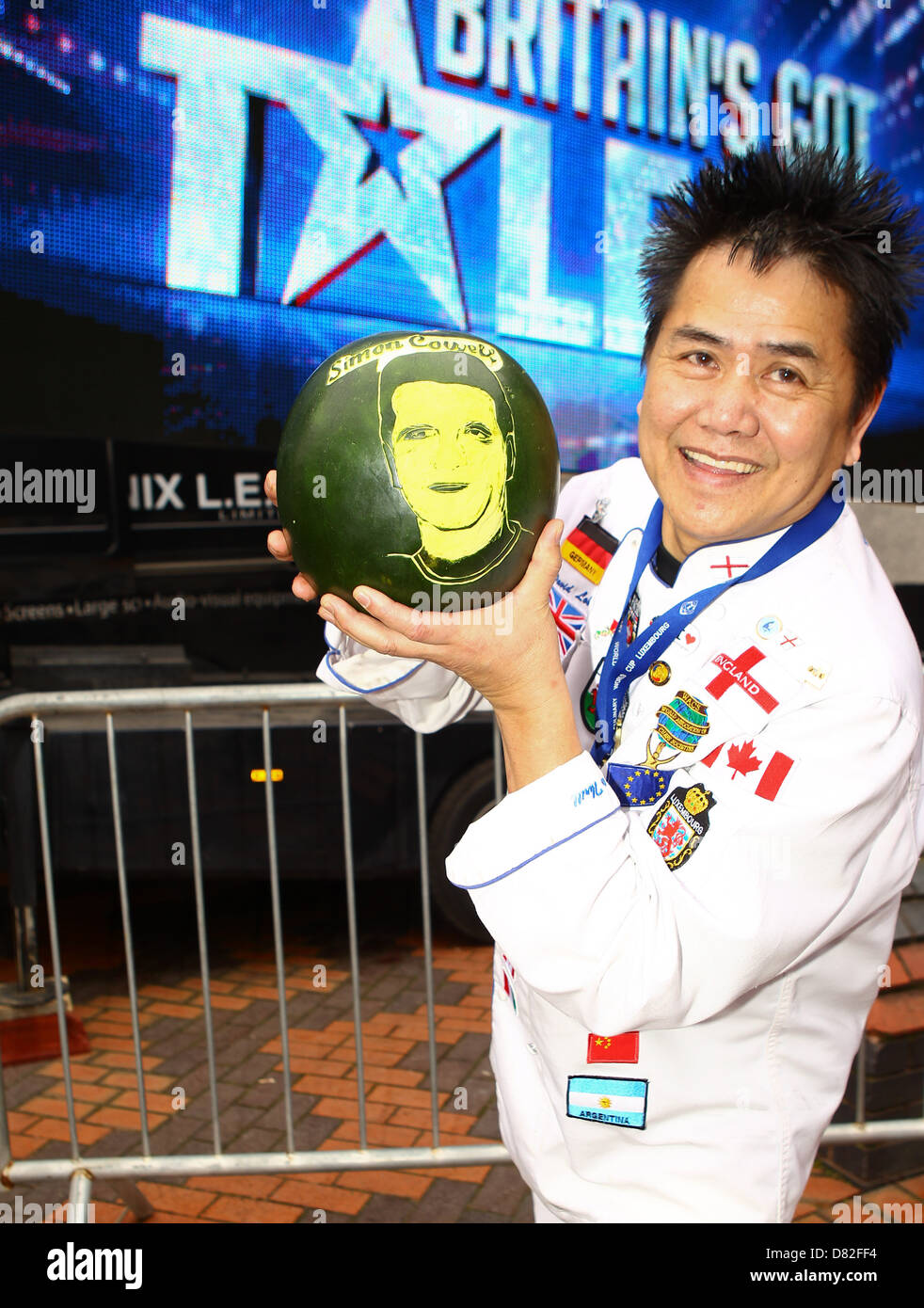 A man shows off a melon featuring the face of Simon Cowell at the ...