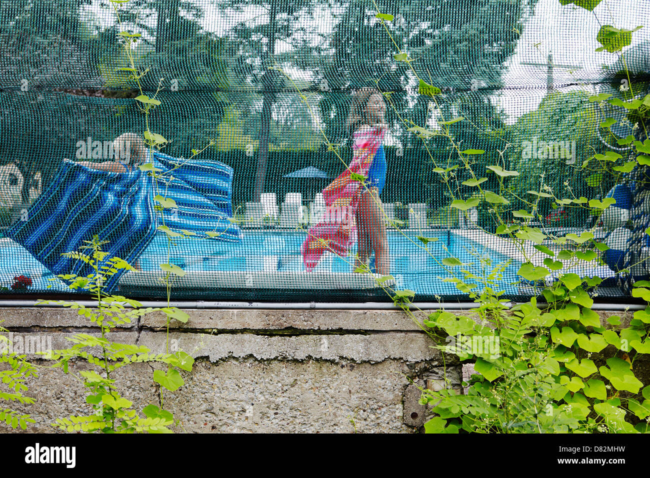 Sisters playing around fenced swimming pool Stock Photo - Alamy