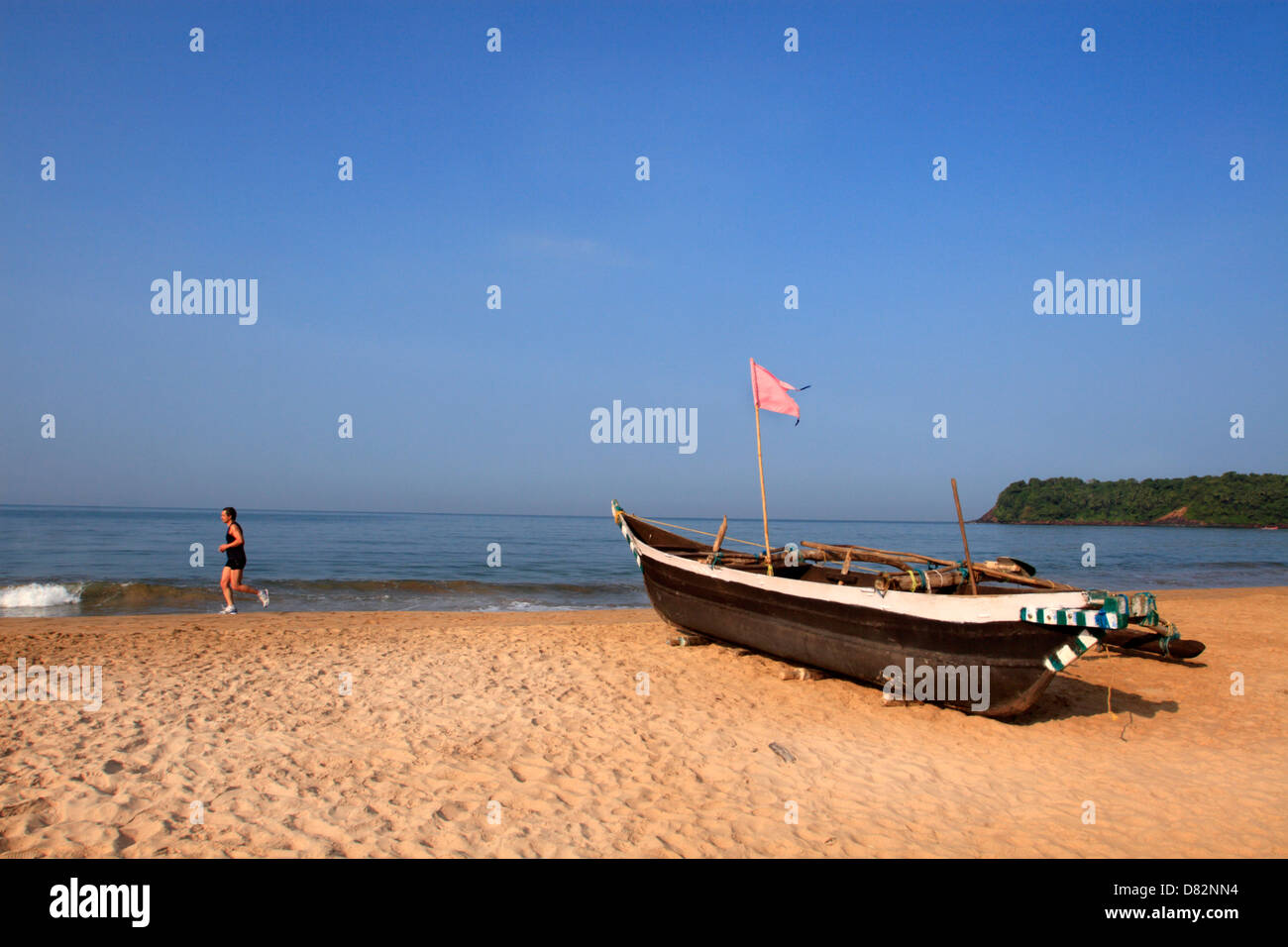 A jogger runs past a traditional wooden outrigger fishing boat on ...