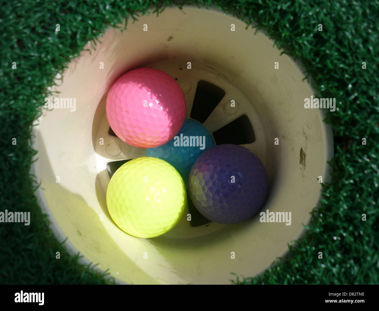 Colored golf balls in a golf hole Stock Photo - Alamy