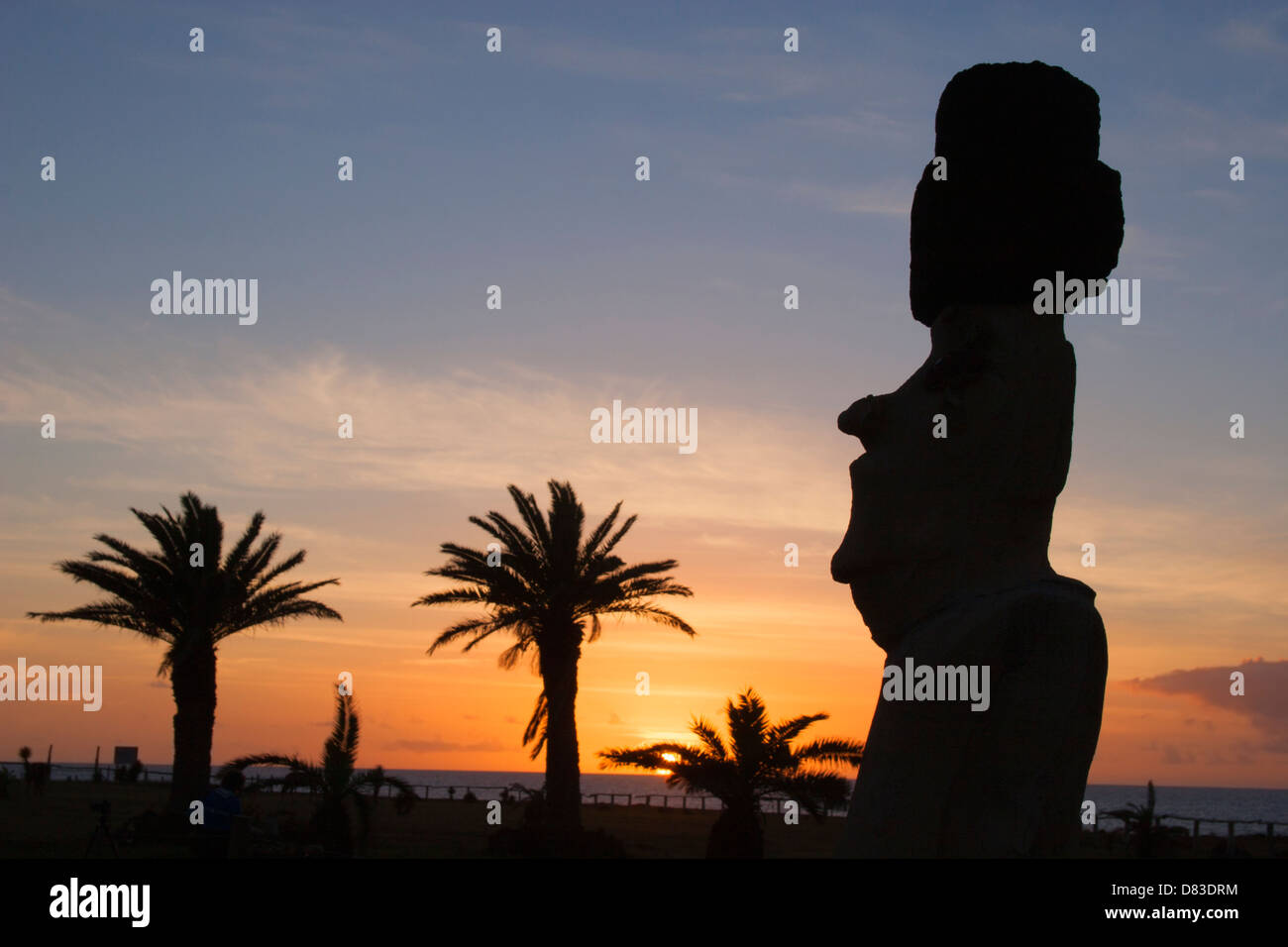 Modern moai statue and palm trees silhouette against orange and blue ...