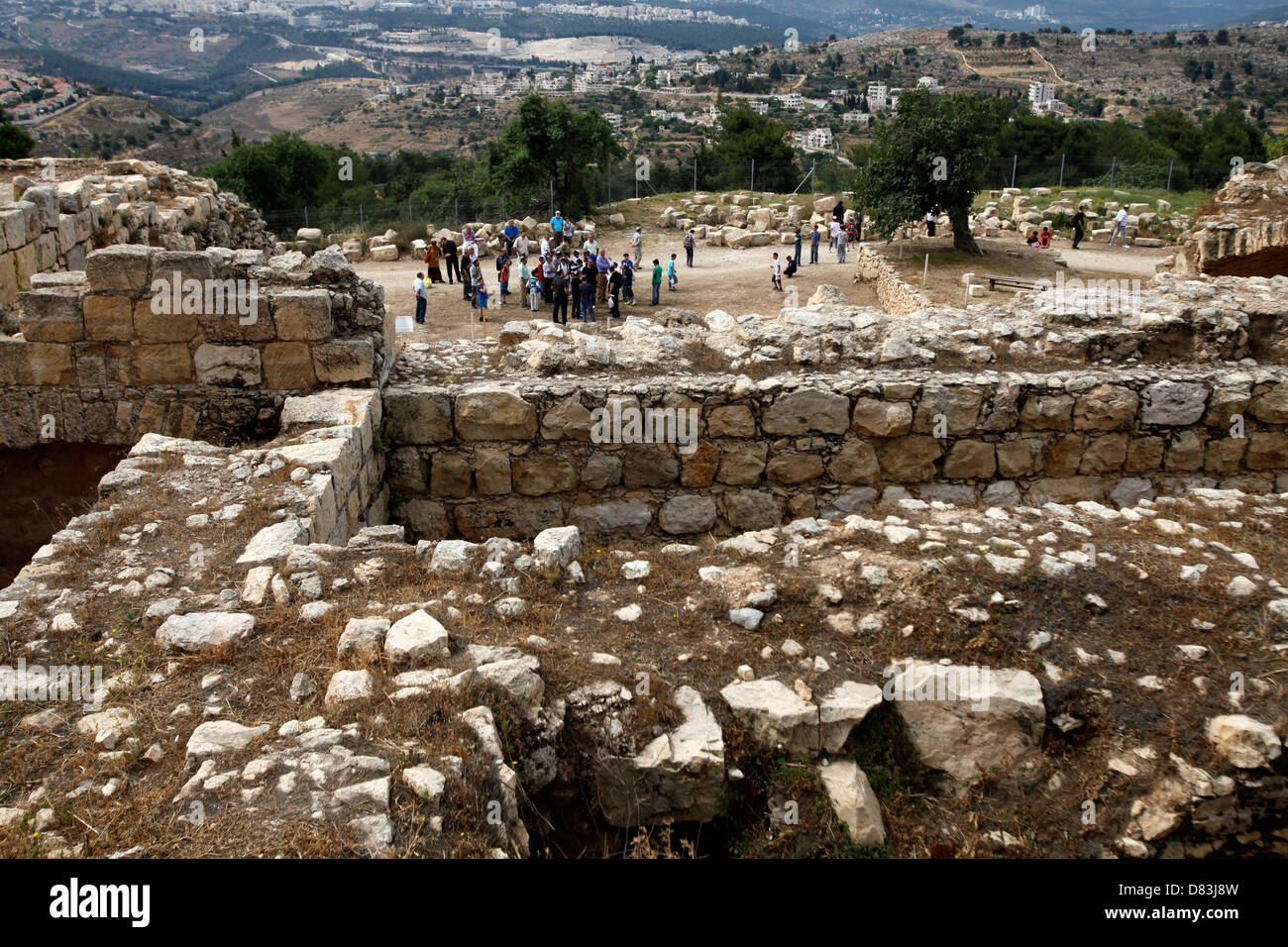 A group of people walk amid ancient ruins of a settlement dating back ...