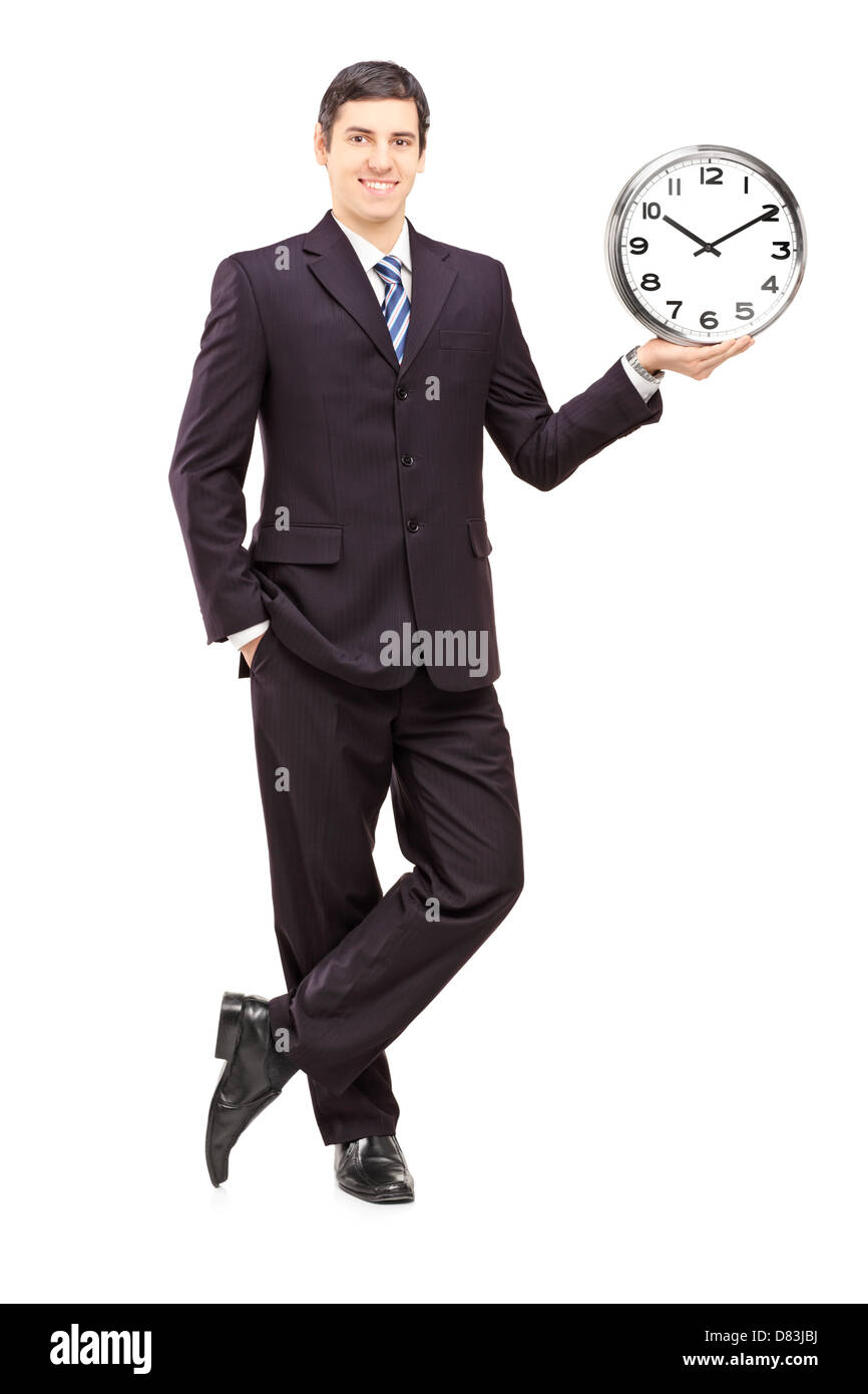 Full length portrait of a young man in suit holding a clock isolated on ...