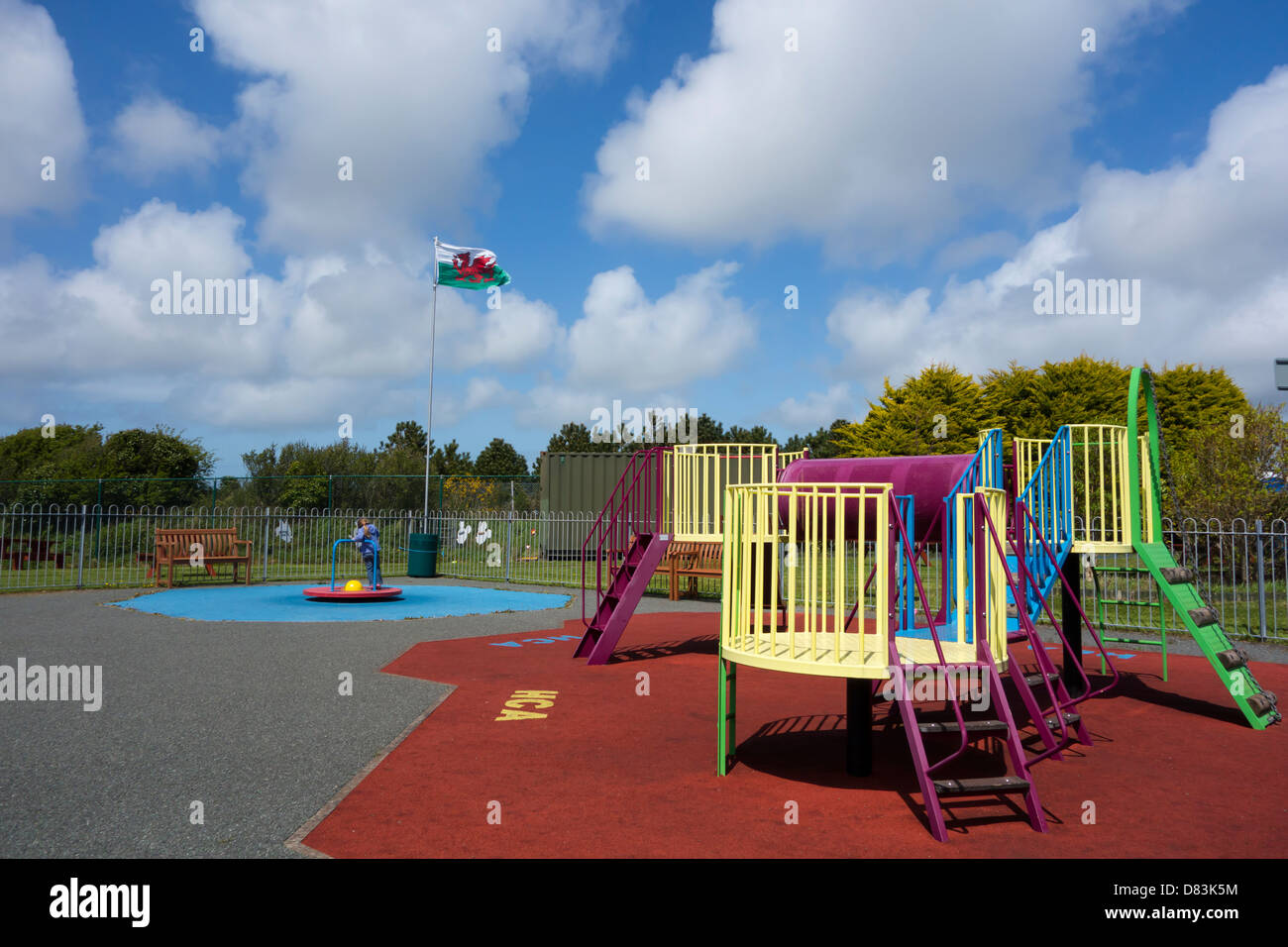 3 year old girl playing on a merry-go-round in a community playground ...