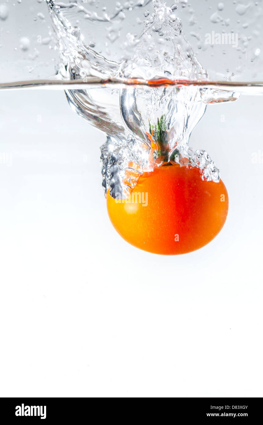 red tomato dropped into the water with blue background Stock Photo - Alamy